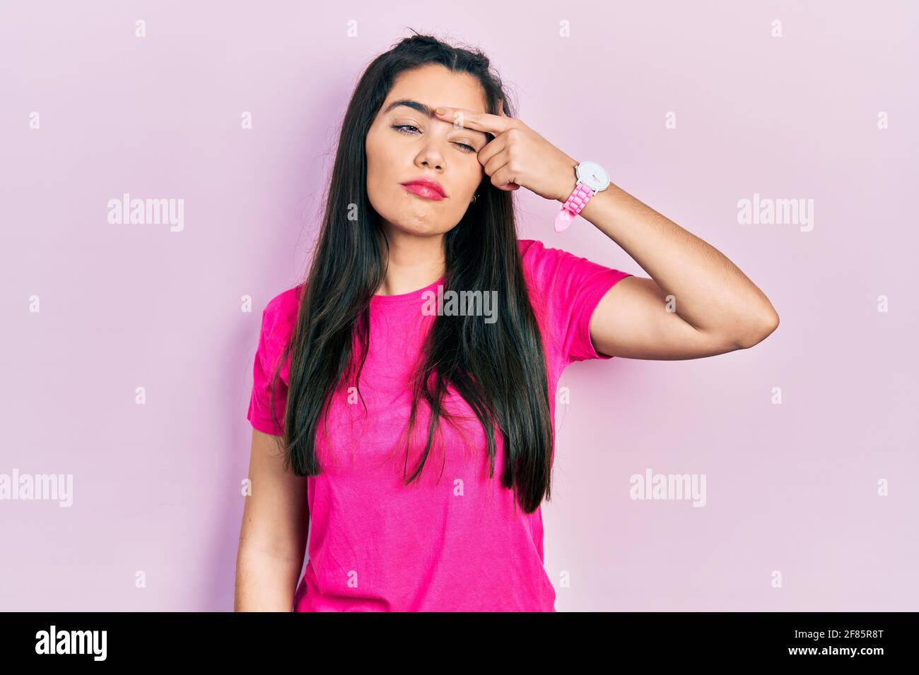 Young hispanic girl wearing casual pink t shirt pointing unhappy to ...