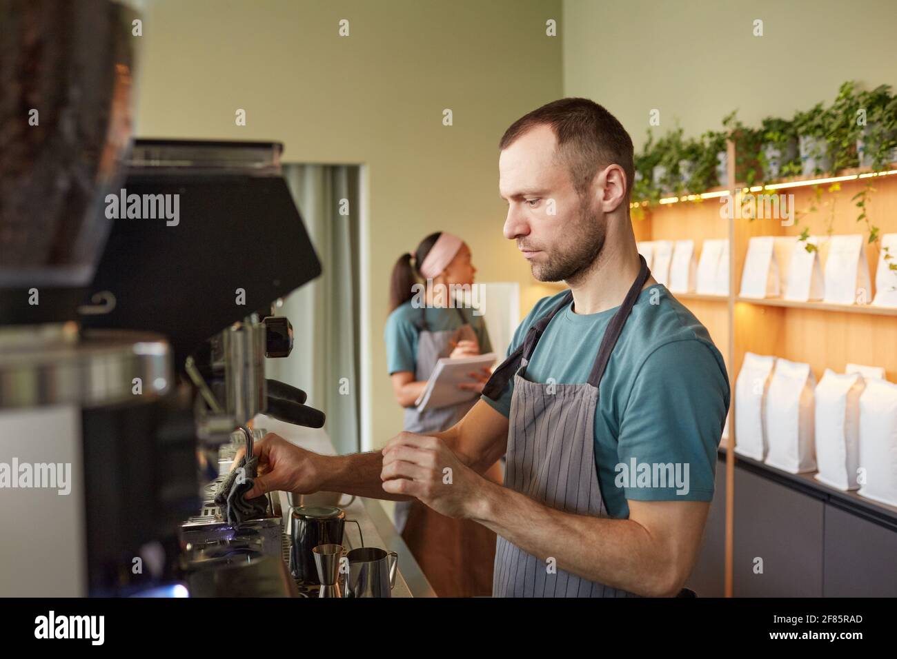 Side view portrait of male barista making fresh coffee in cafe while ...