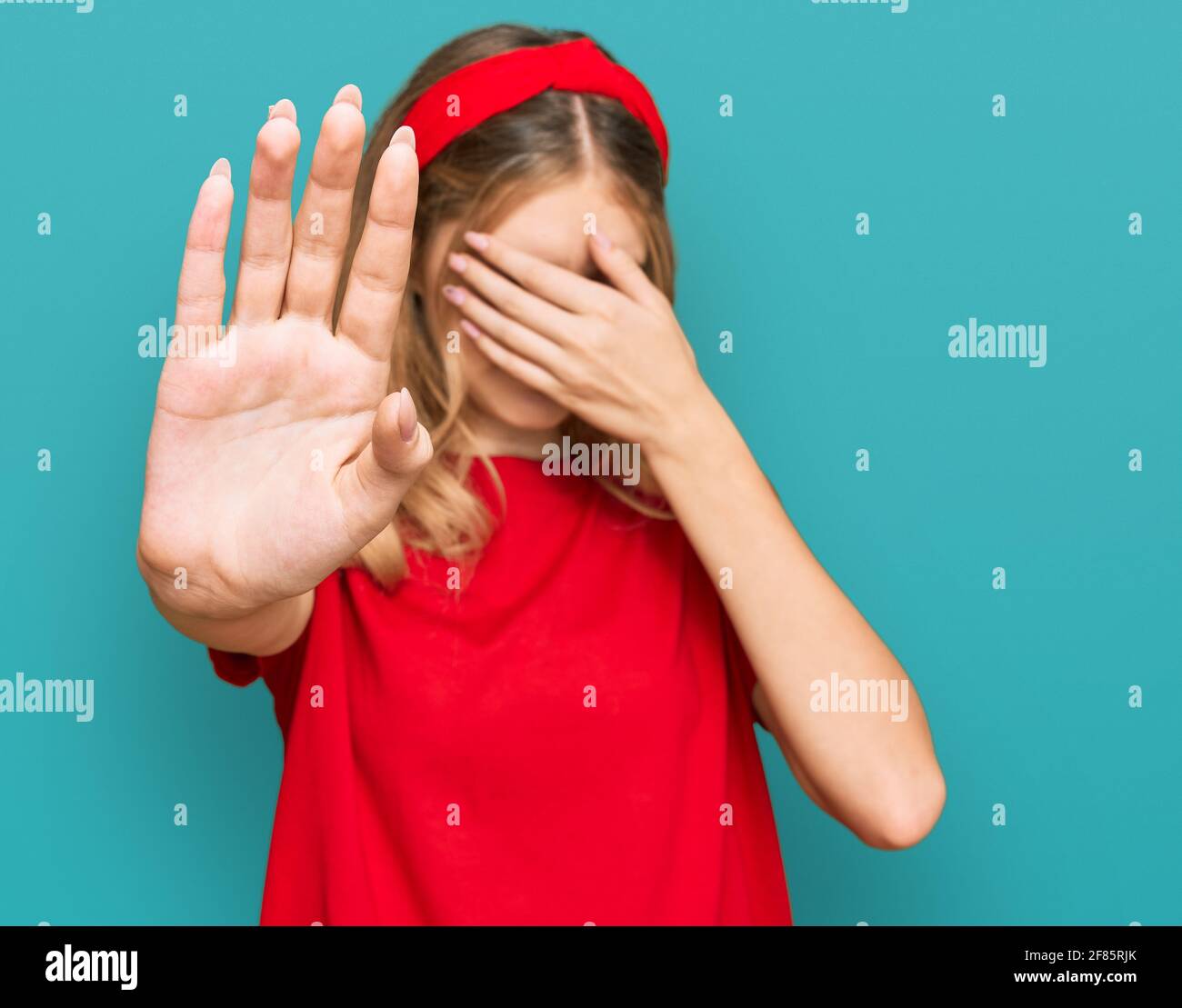 Beautiful young caucasian girl wearing casual red t shirt covering eyes ...