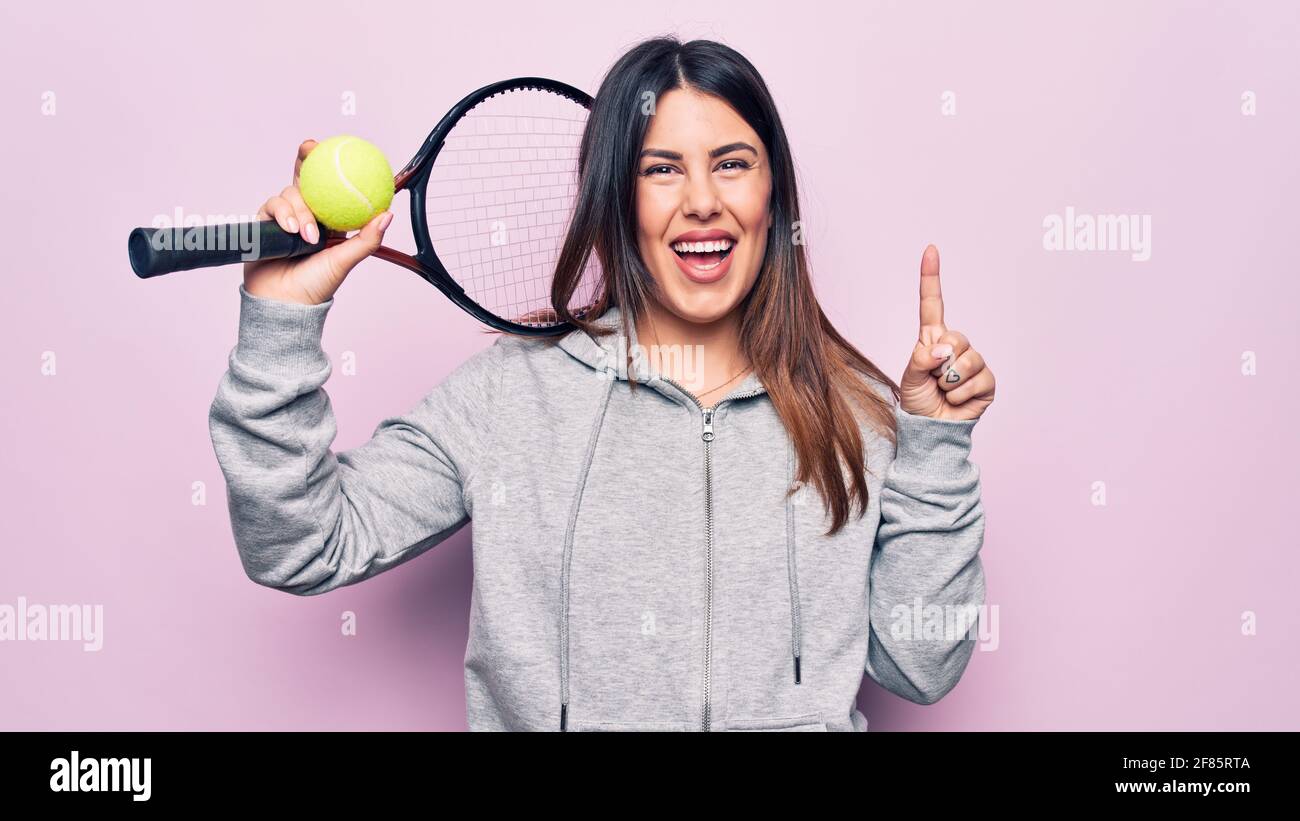 Young beautiful sportswoman playing tennis using racket and ball over ...