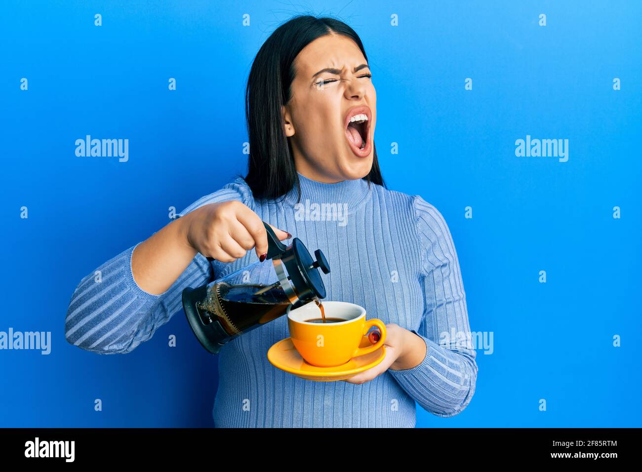 Beautiful brunette woman holding french coffee maker pouring coffee on ...