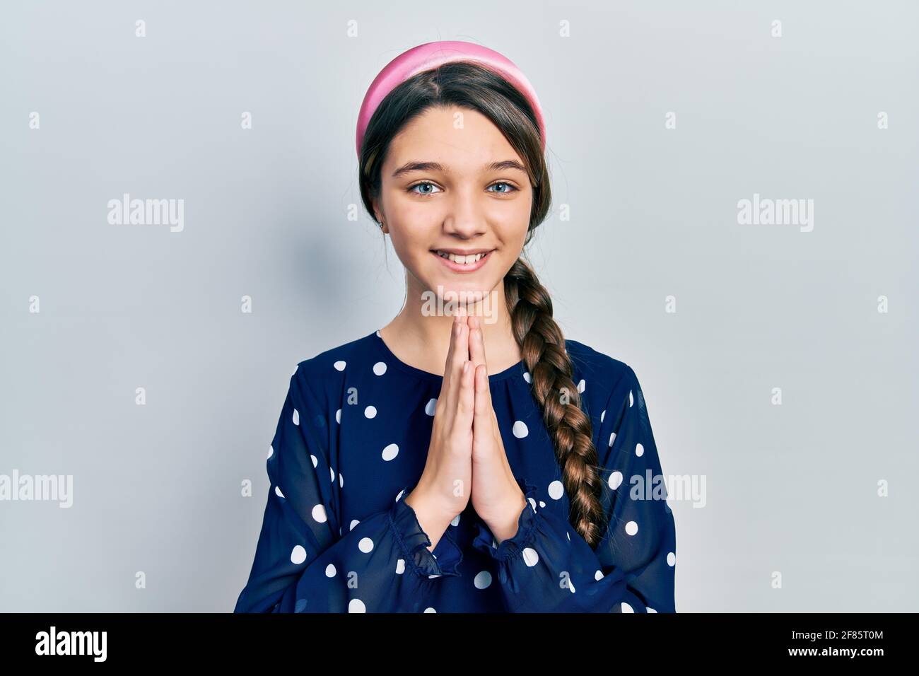 Young brunette girl wearing elegant look praying with hands together ...