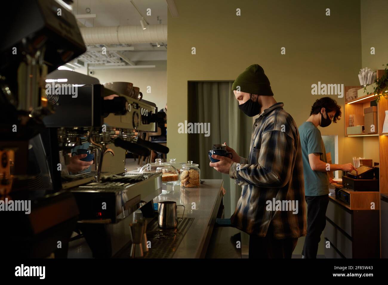 Side view portrait of male barista making fresh coffee while working at ...