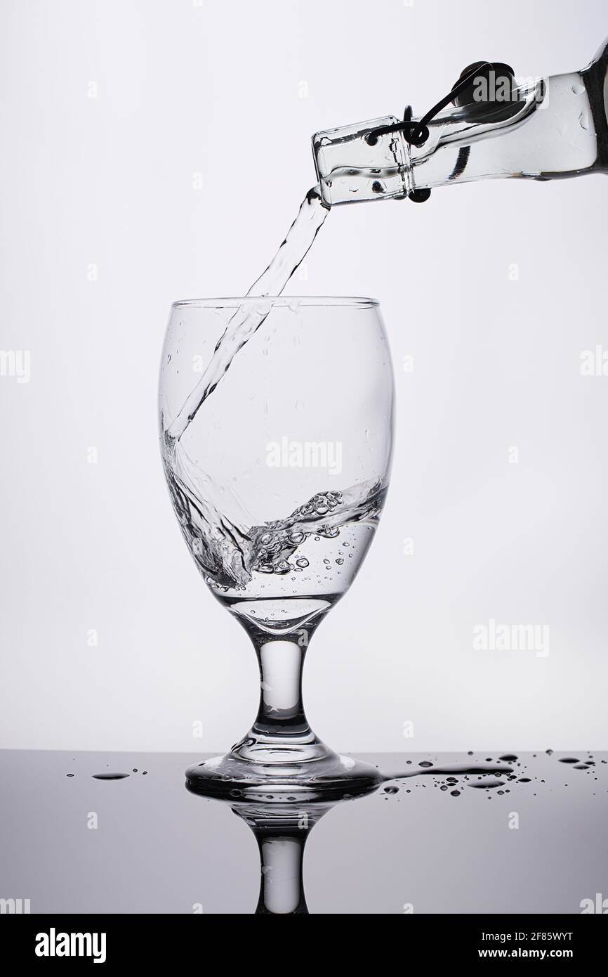 A studio photo of pouring water from a bottle into a glass against a ...