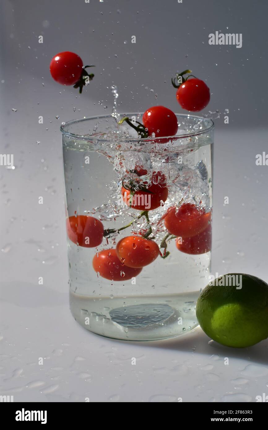 Vertical shot of vegetables fallen into a glass jar causing water ...