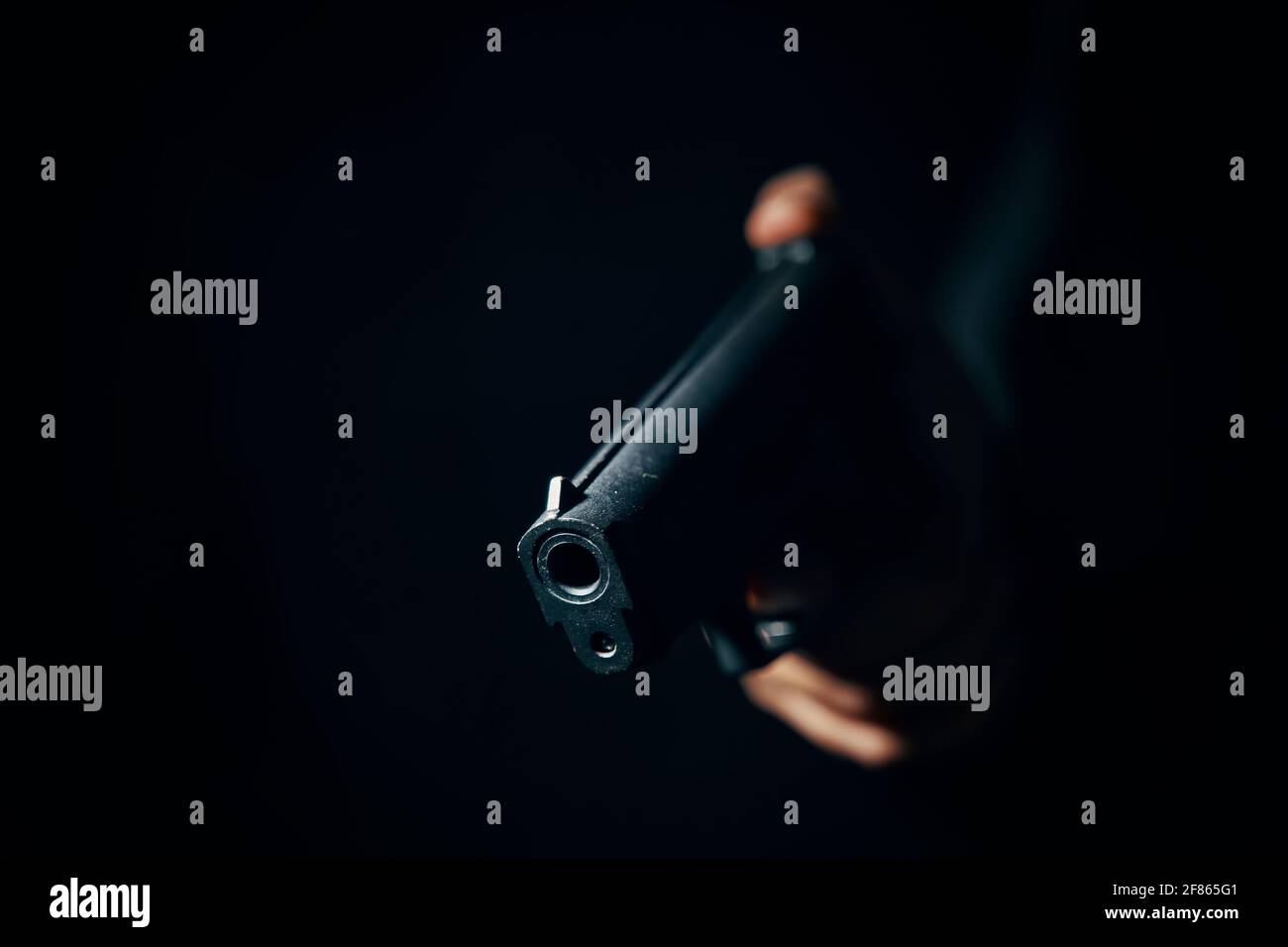 Close-up of black gun in hand on dark background. Firearms in shadows ...
