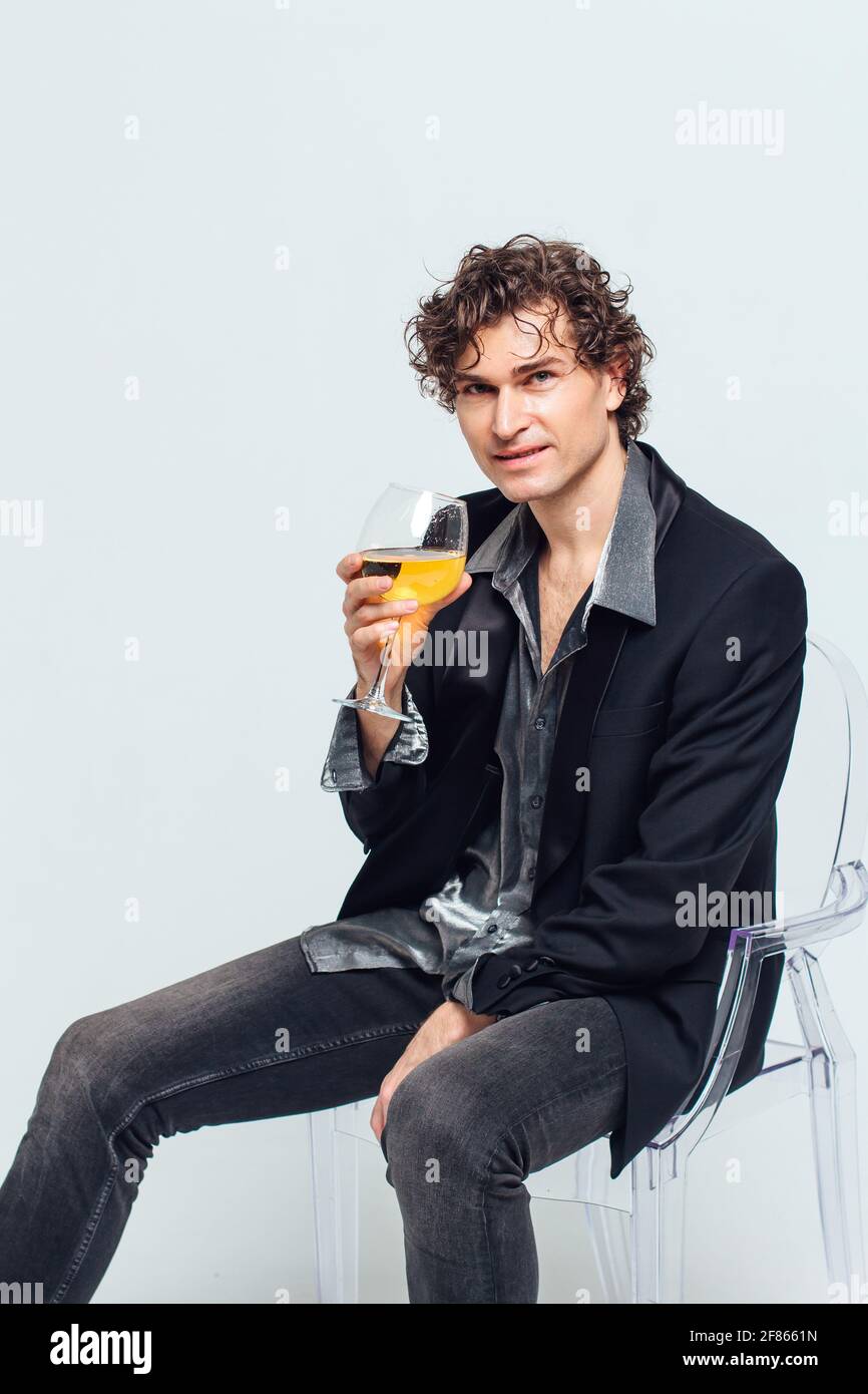 Tall handsome confident young man in a jacket sitting on the chair and ...