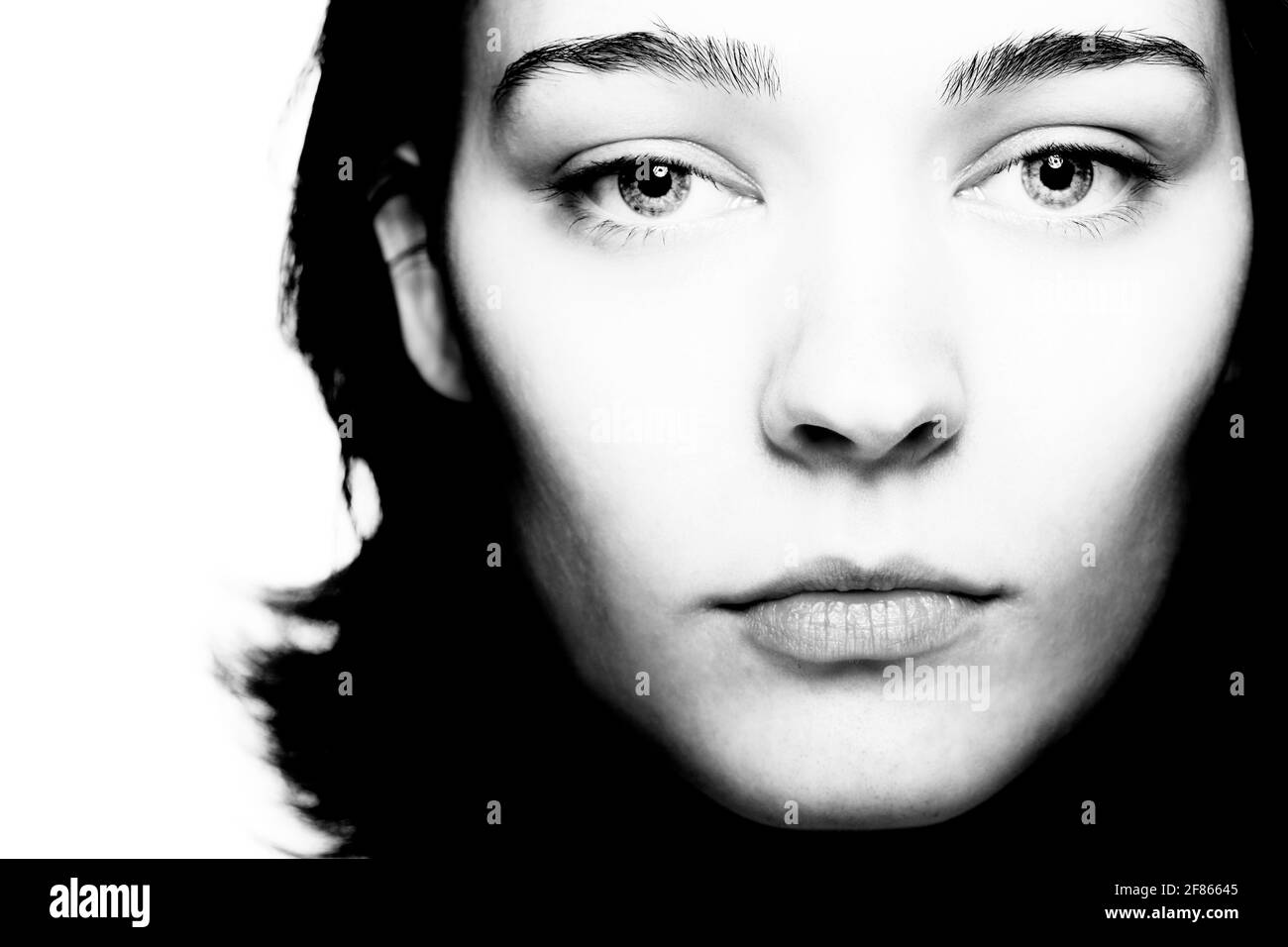 black and white studio portrait of a beautiful young woman against ...
