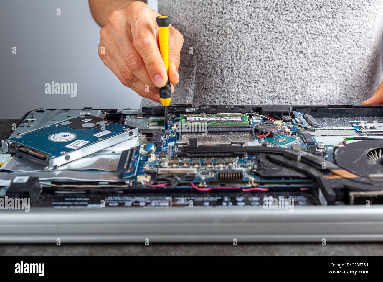 A computer technician is repairing an old laptop using a screw driver ...