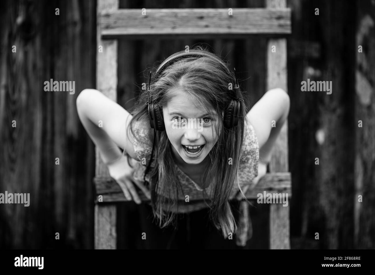 Little girl enjoy music with headphones outdoors. Black and white photo ...