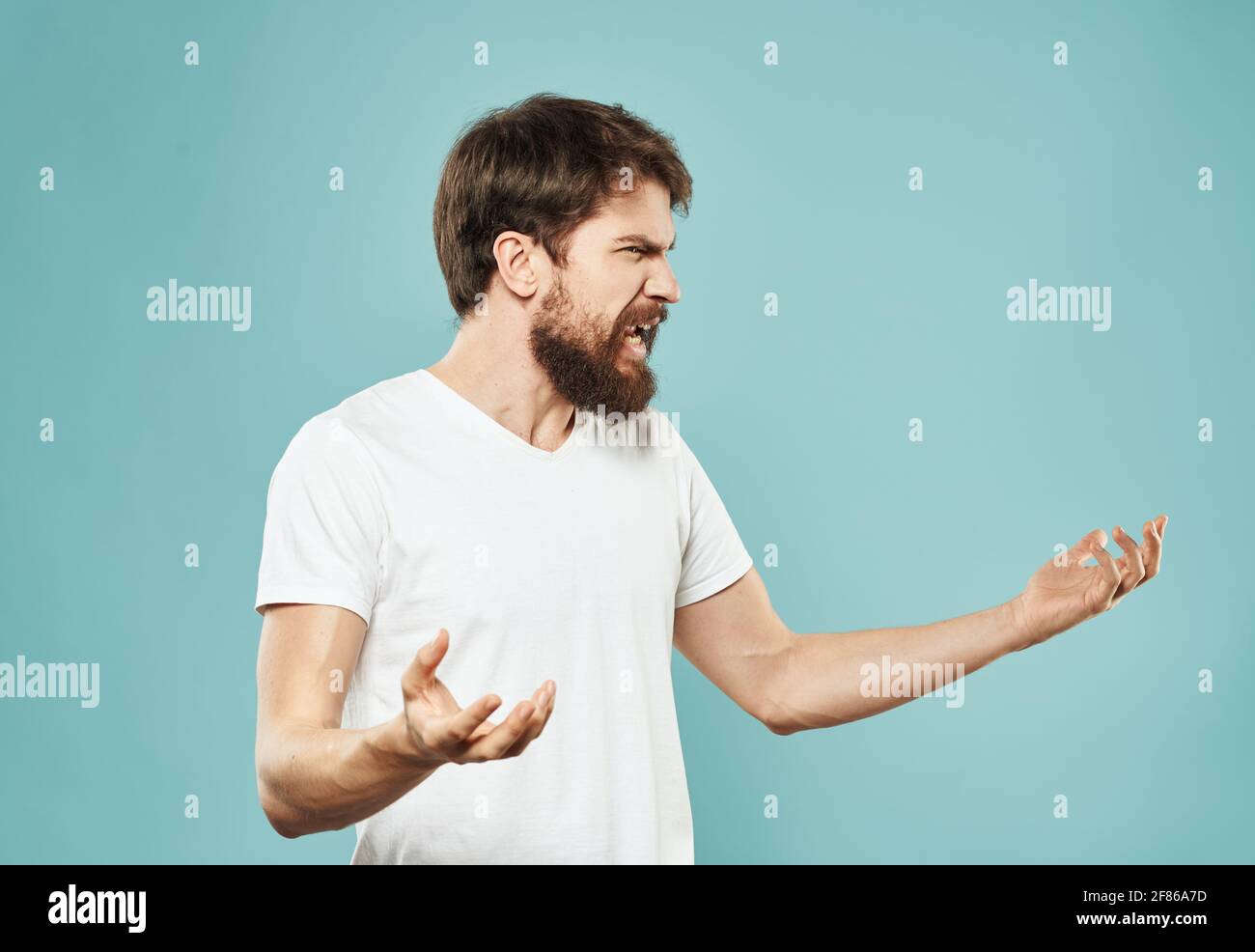 Angry guy gesturing with his hands on a blue background cropped with ...
