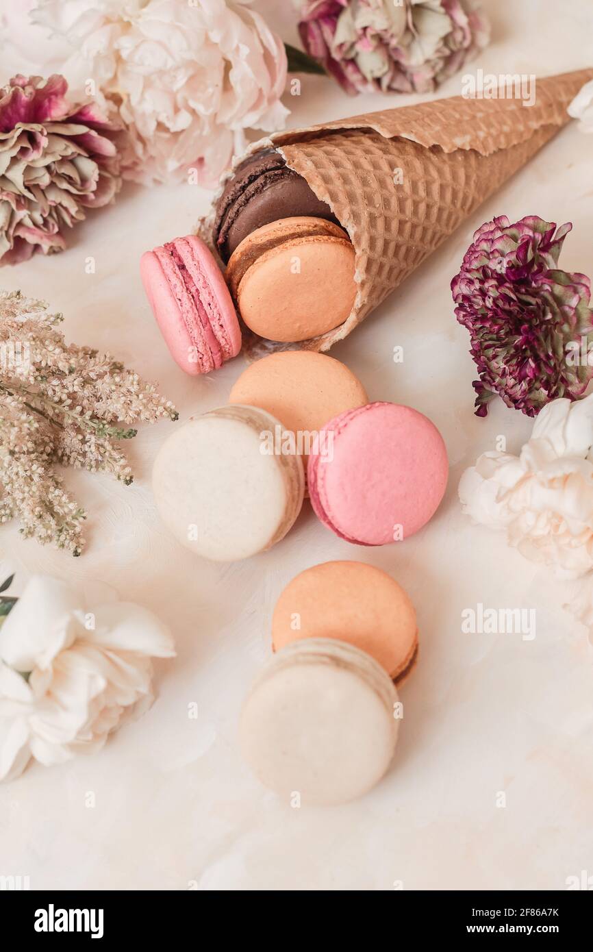 French macaroons in pastel colors with beautiful flowers on a white ...