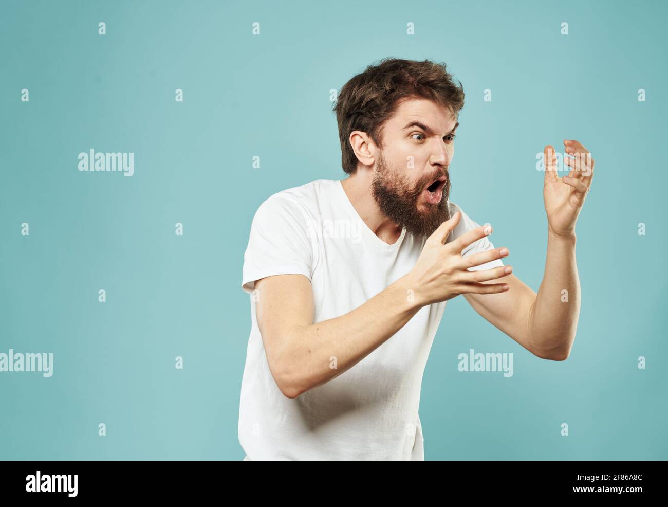 Angry guy gesturing with his hands on a blue background cropped with ...