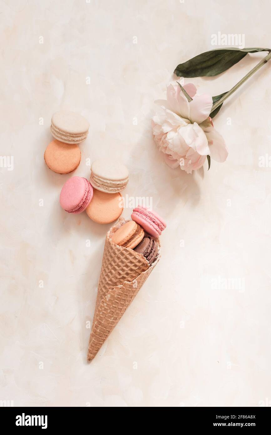 Top view of the sweet colorful macarons in the waffle cone on the light brown surface Stock ...