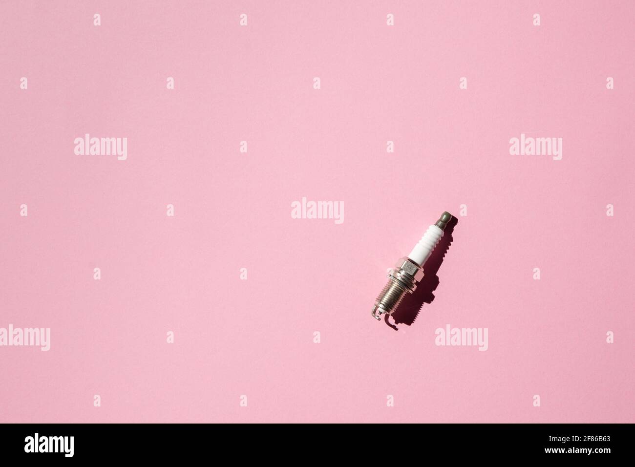 Spark plug. Car candle lies against a pink background. Auto engine ...