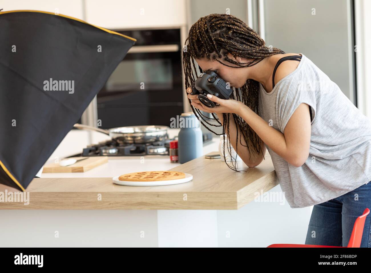 Young female photographer photographing food in the kitchen leaning ...