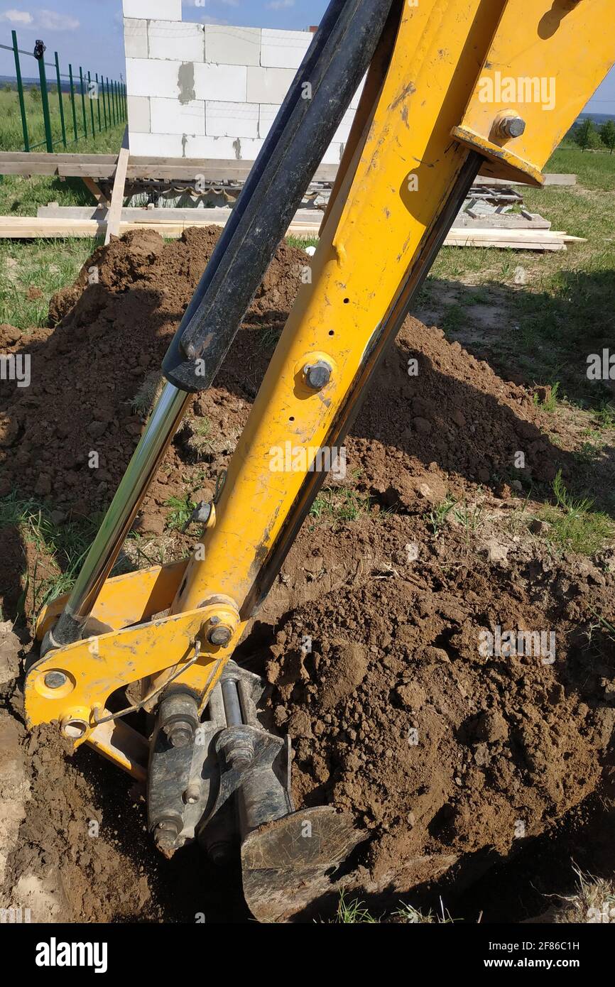 The yellow excavator digs a trench, construction works by means of ...