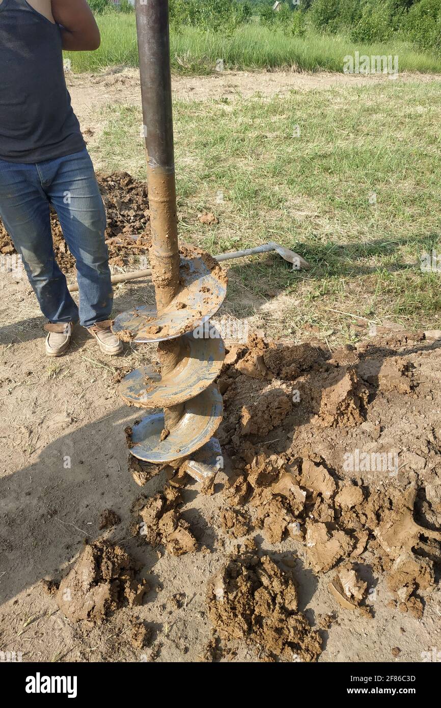 Workers are drilling pits for poles, starting work with a hand drill ...