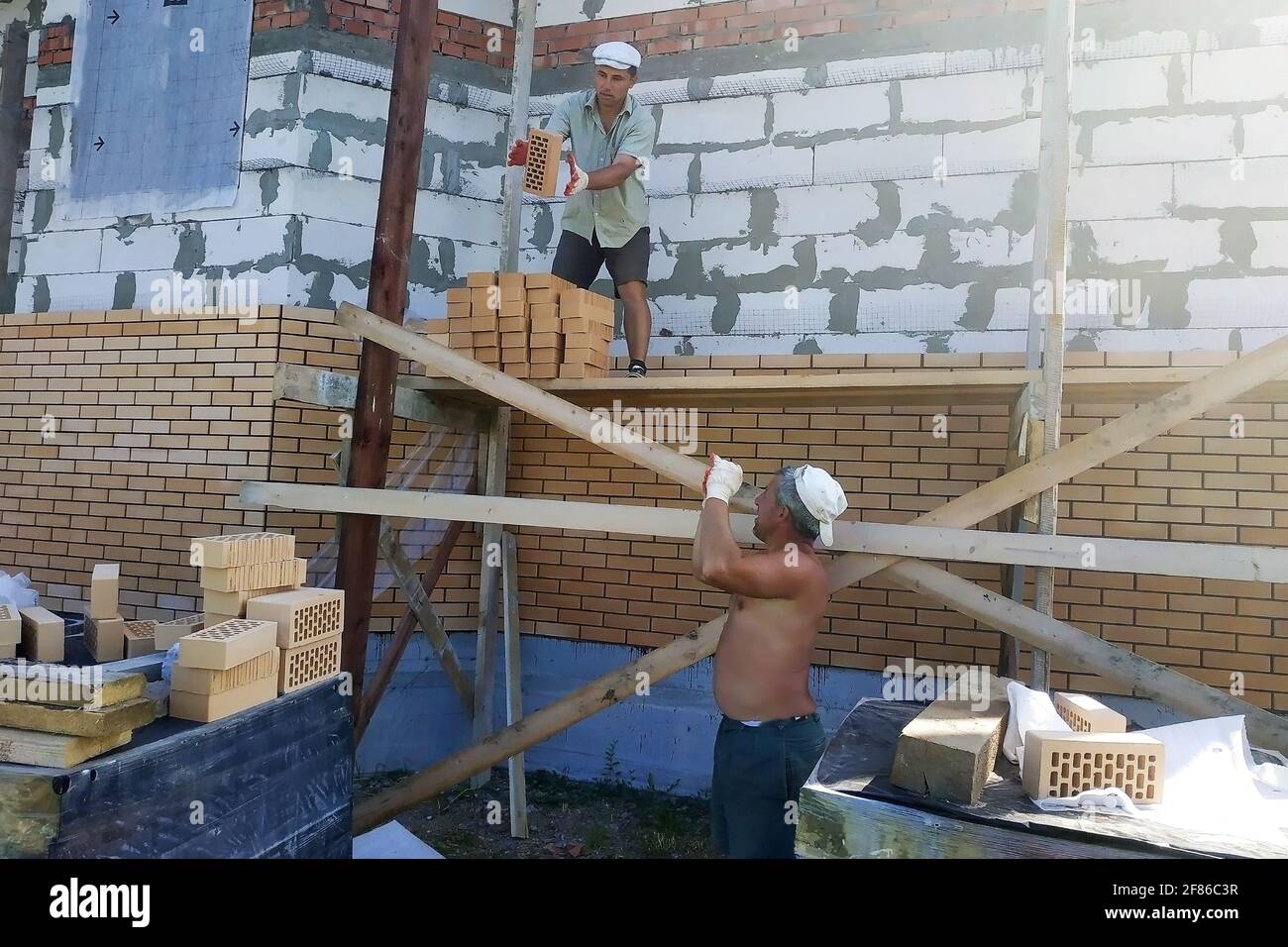 A worker throws bricks at another worker, construction work in a ...