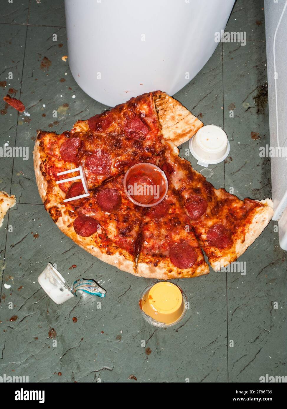Old half eaten pizza left over after a wild party in a messy house ...