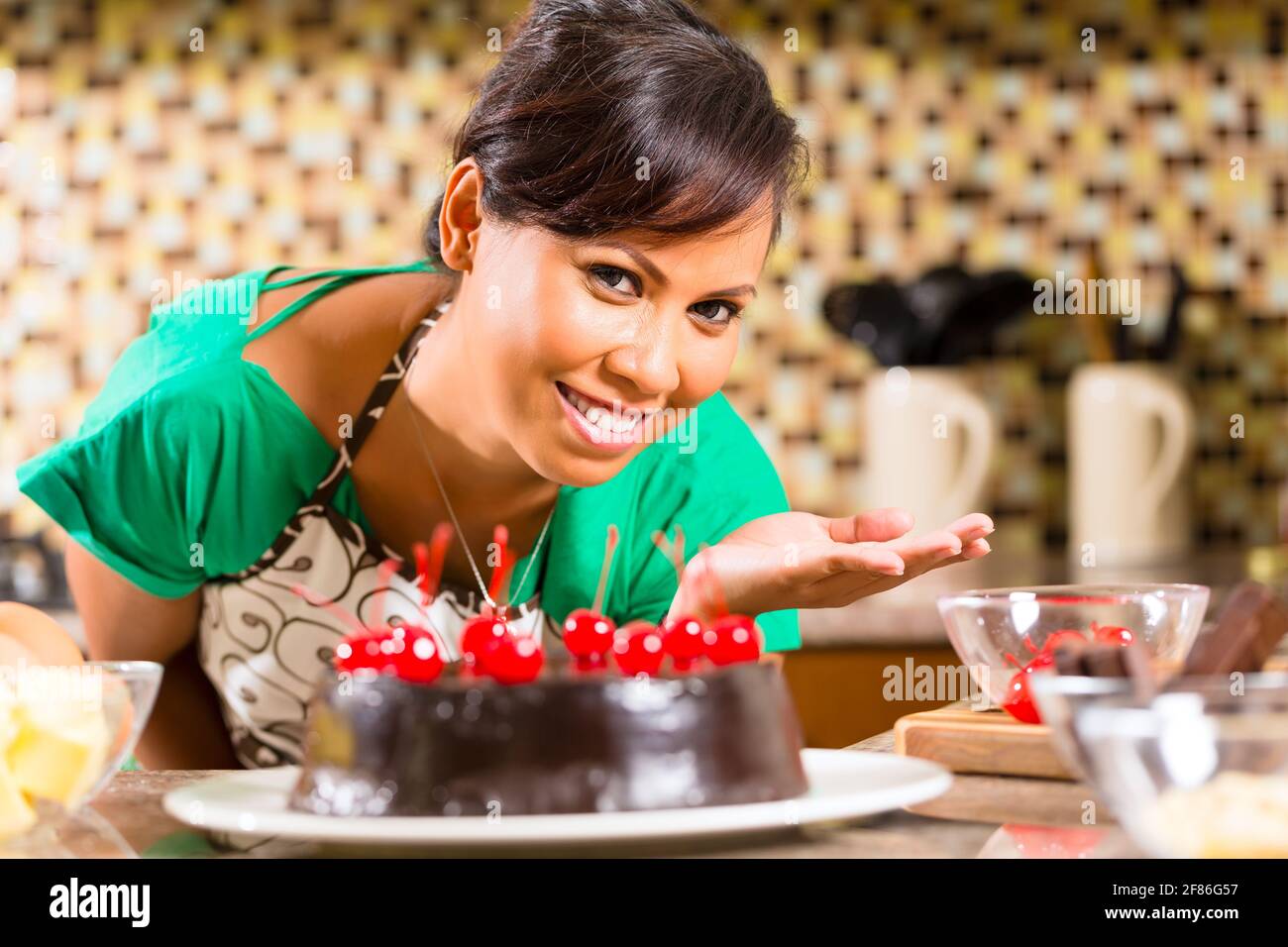 Asian woman presenting homemade chocolate cake with cherries she baked ...