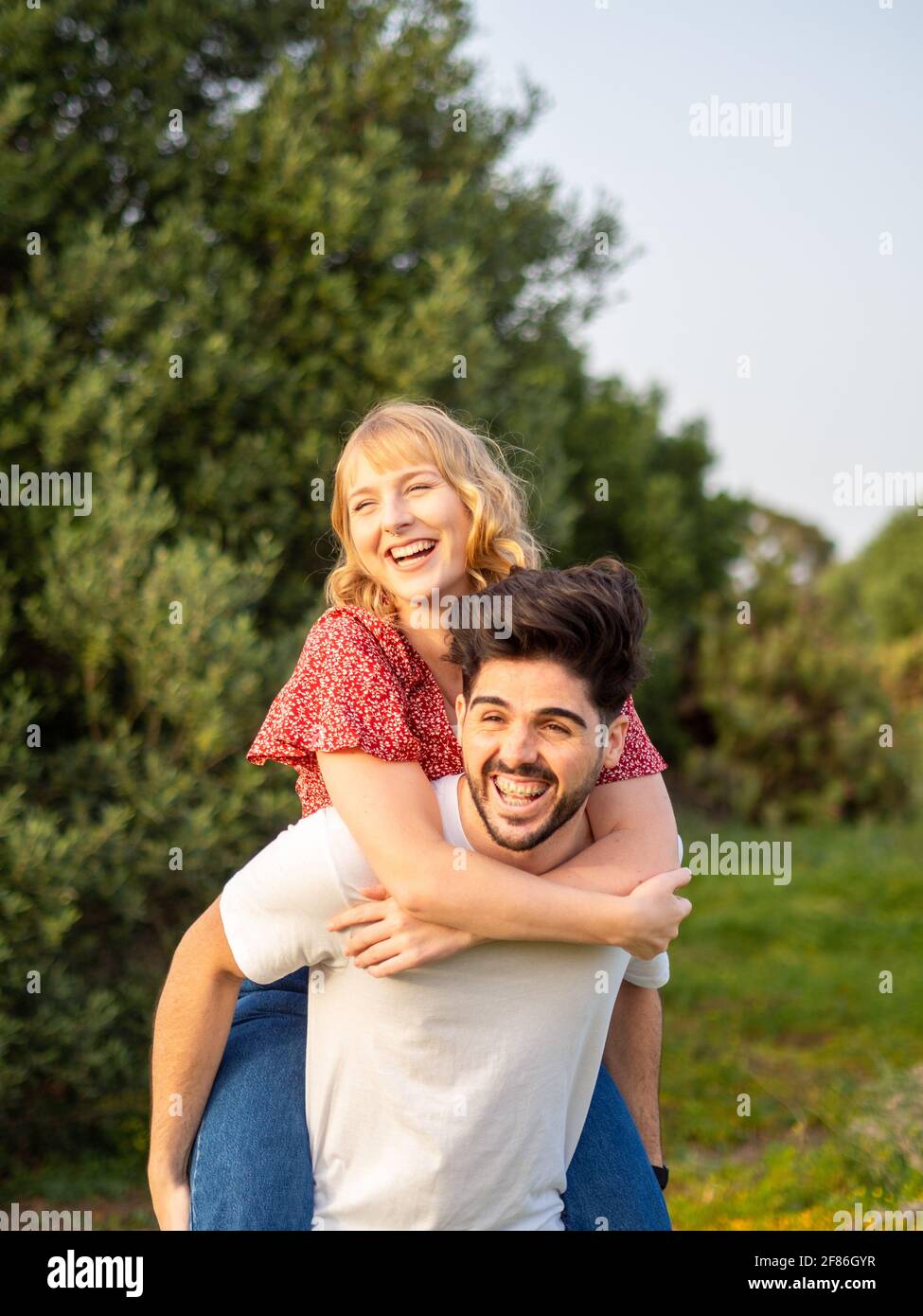 Young Spanish couple is having fun in the park; a guy is giving a ...
