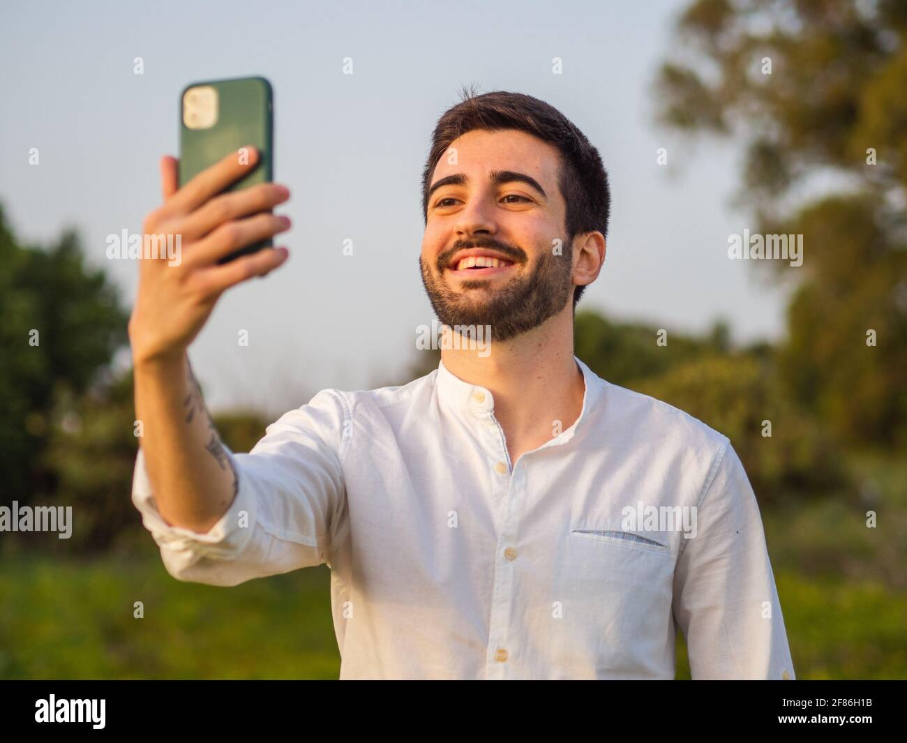 Happy handsome Spanish guy taking a selfie in the park Stock Photo - Alamy