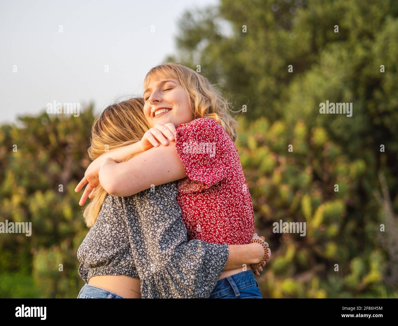 Happy hugging female friends having fun in the park Stock Photo - Alamy