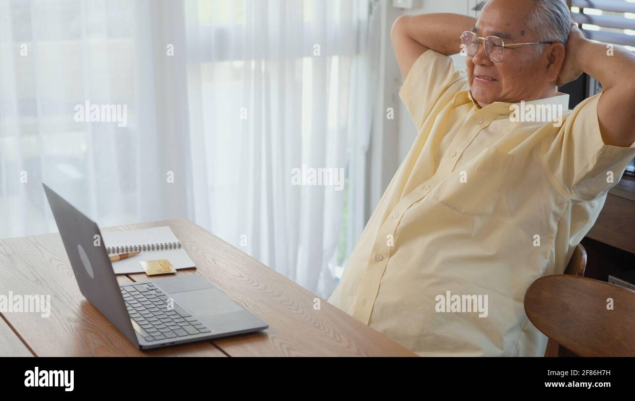 Senior man dressed wear eyeglasses sitting on chair working on laptop ...