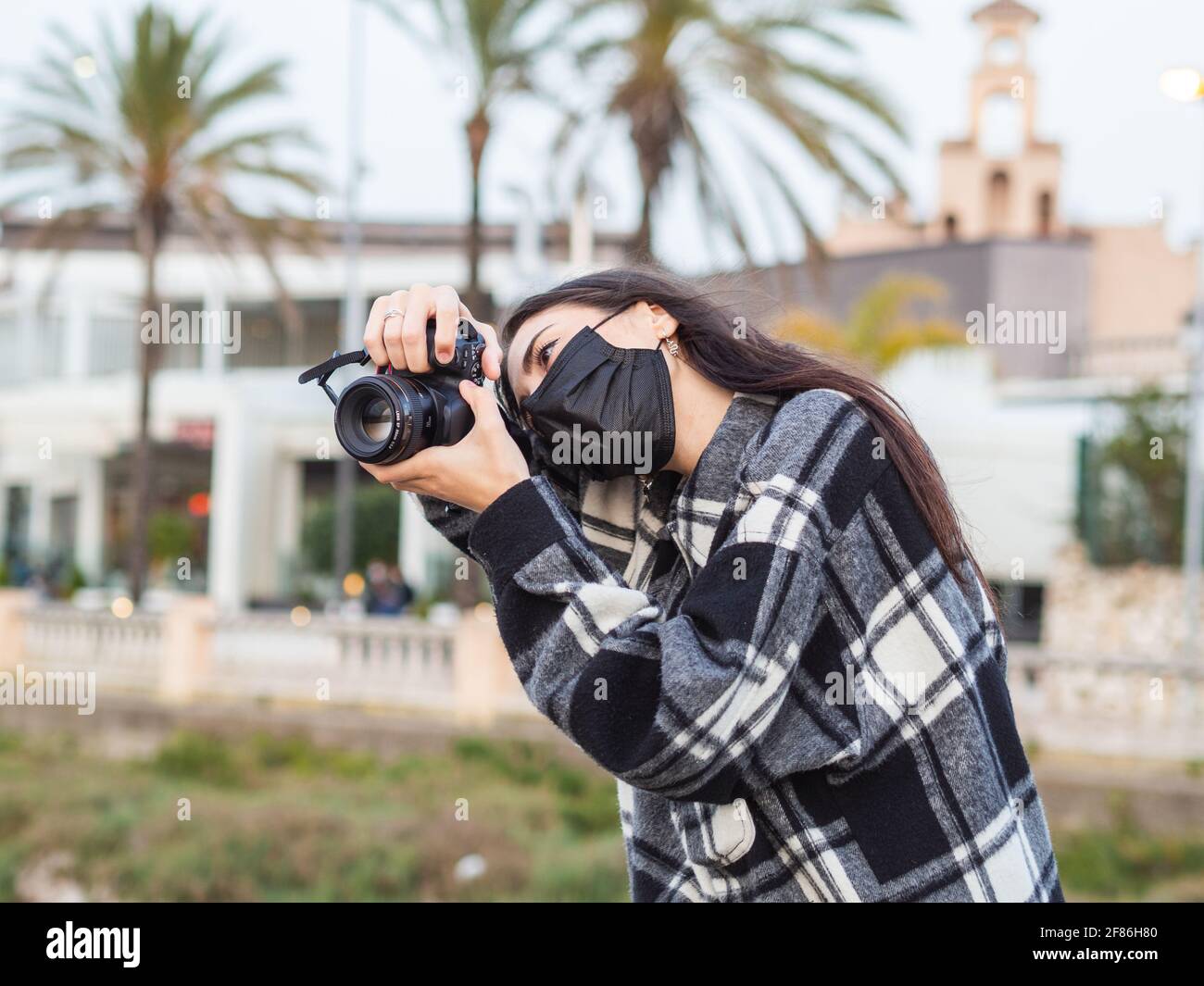 Young Spanish female wearing a black face mask and a checkered shirt is ...