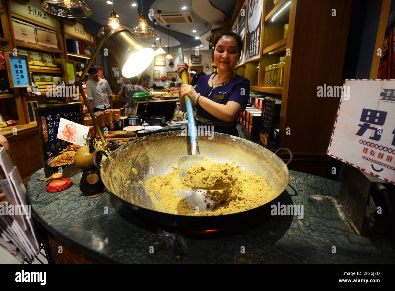 A Chinese woman stirring fish floss in a street food market in Xiamen ...