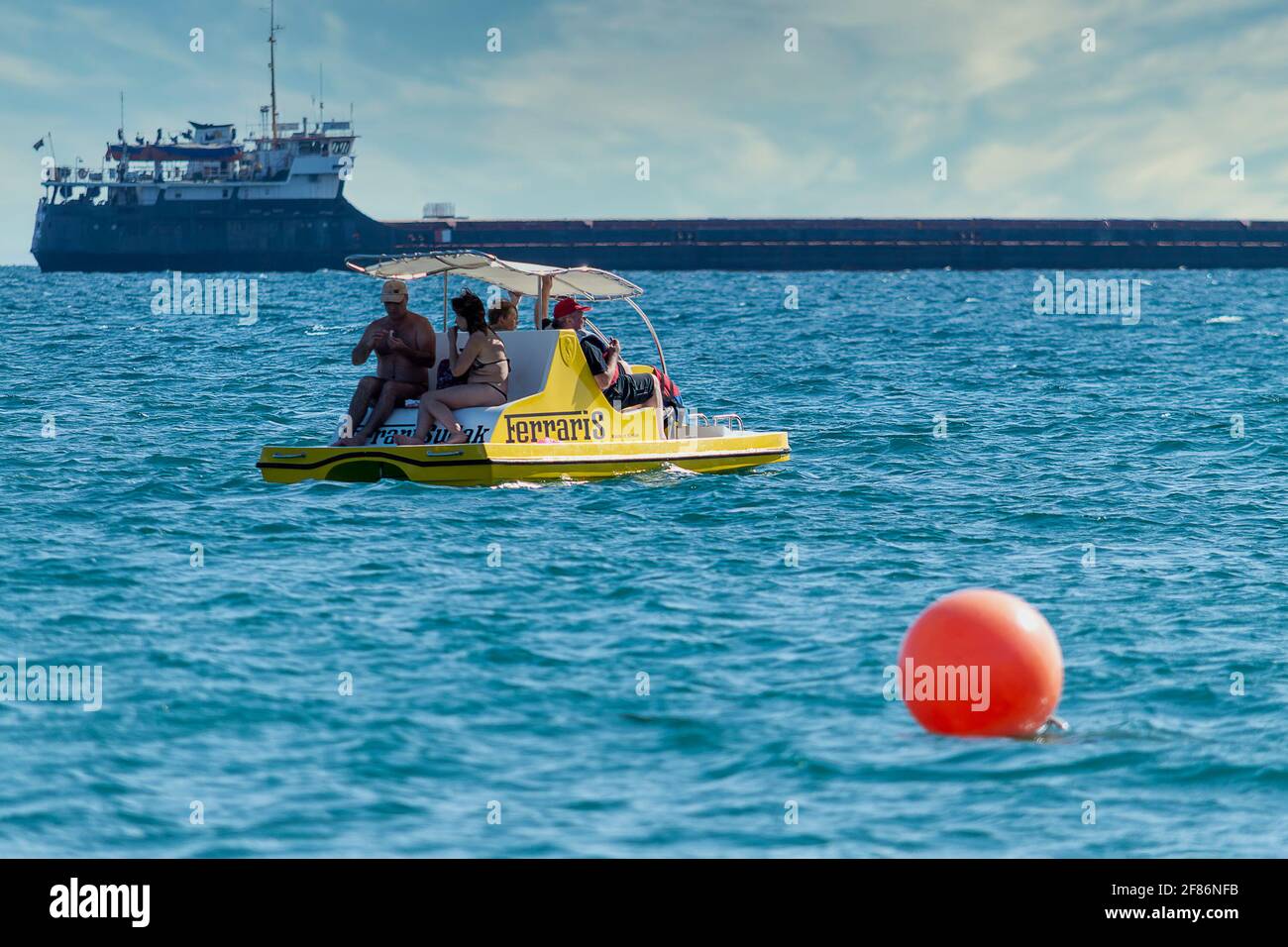 Pleasure catamaran boat at sea and large cargo ship in background ...
