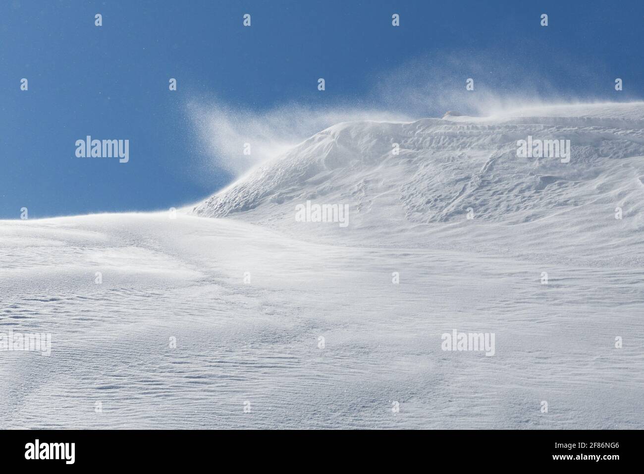 cold winter storm with wind blowing over snow cornice in snowy ...
