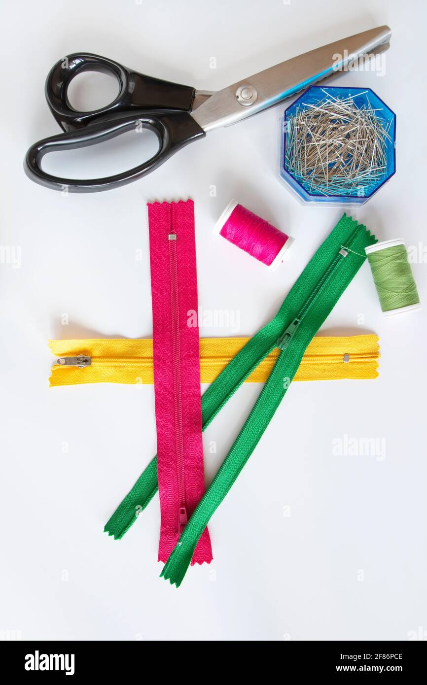 pink, red, yellow zippers, Scissors and box of round pin . Selective ...
