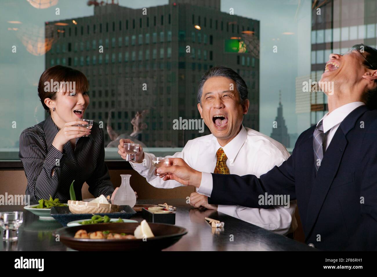 Happy business people laughing at lunch in highrise restaurant Stock ...