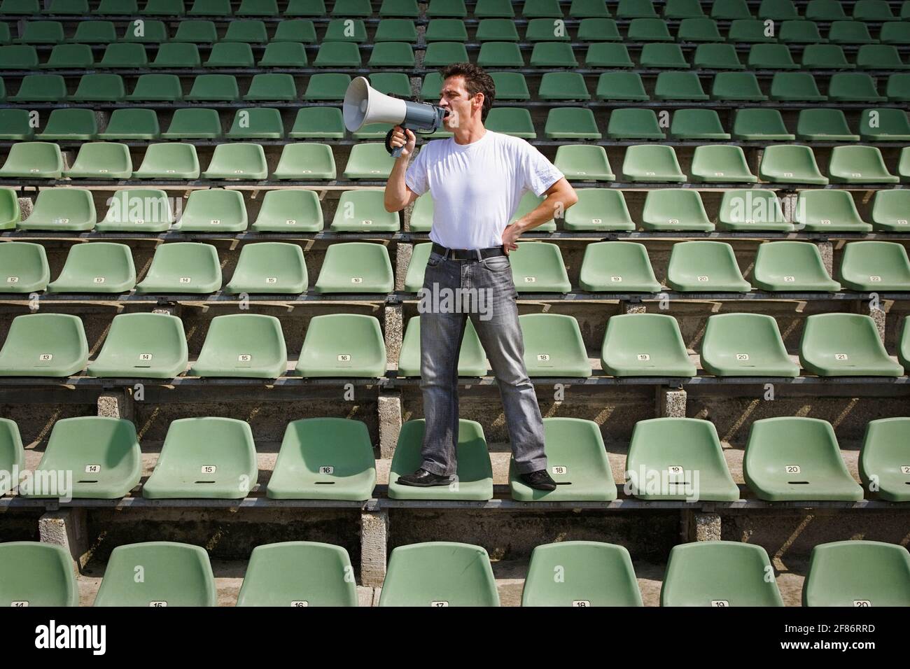 Man yelling into bullhorn on green stadium seats Stock Photo - Alamy