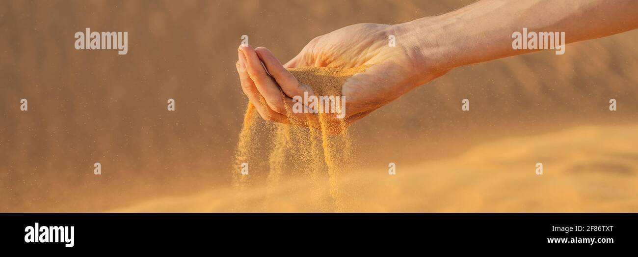 Desert, sand puffs through the fingers of a mans hand BANNER, LONG ...