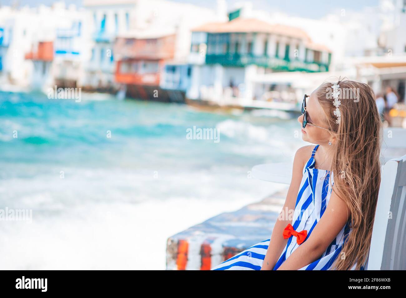 Adorable little girl at old street of typical greek traditional village ...