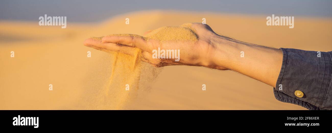 Desert, sand puffs through the fingers of a mans hand BANNER, LONG ...