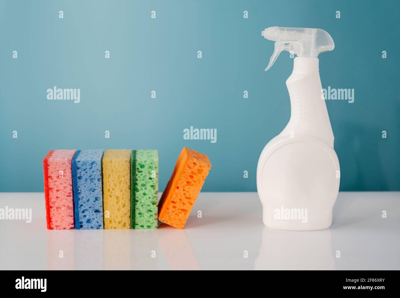 Colorful cleaning sponges and white sprinkle bottle on blue background ...