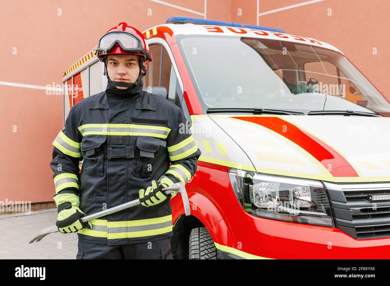 A man of strong physique in uniform and helmet stands by a rescue ...