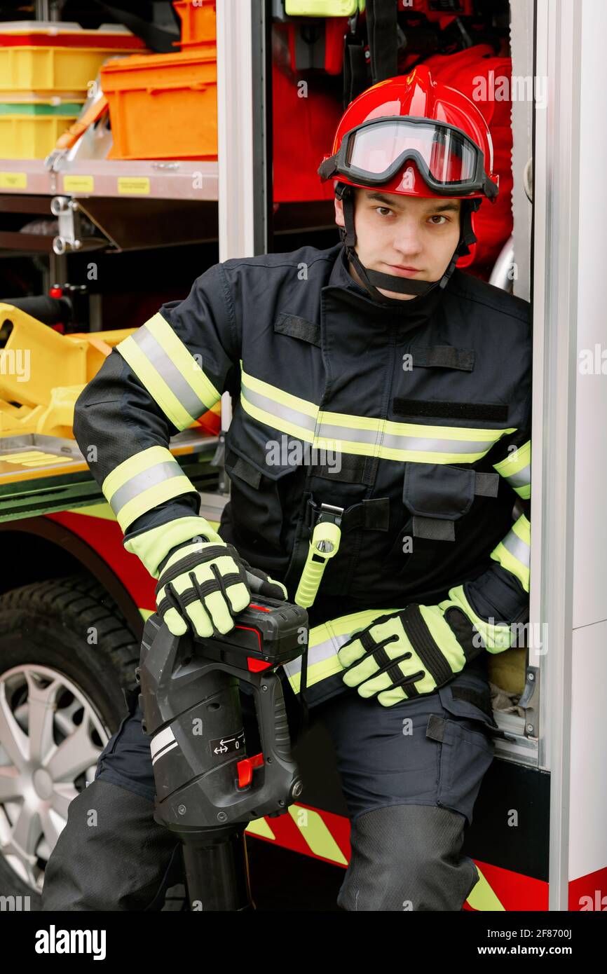A man of strong physique in uniform and helmet stands by a rescue ...