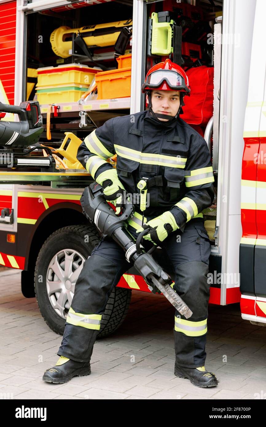 A man of strong physique in uniform and helmet stands by a rescue ...