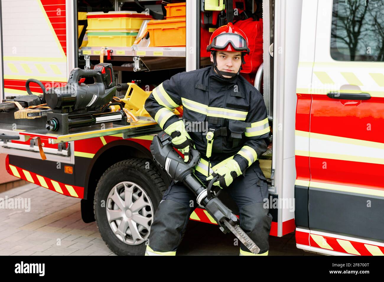A man of strong physique in uniform and helmet stands by a rescue ...