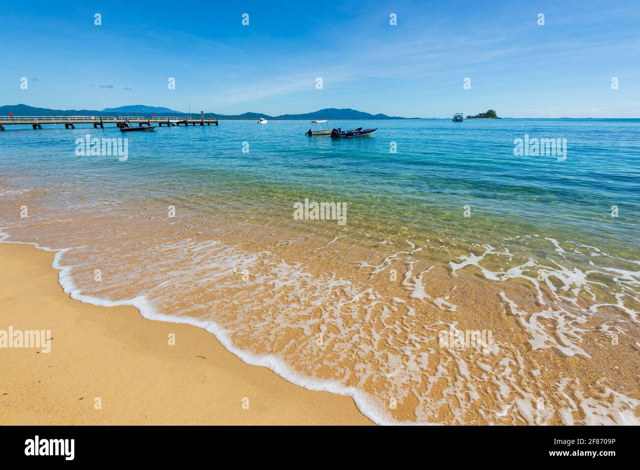Turquoise waters and gentle lapping waves on the beach at Dunk Island ...