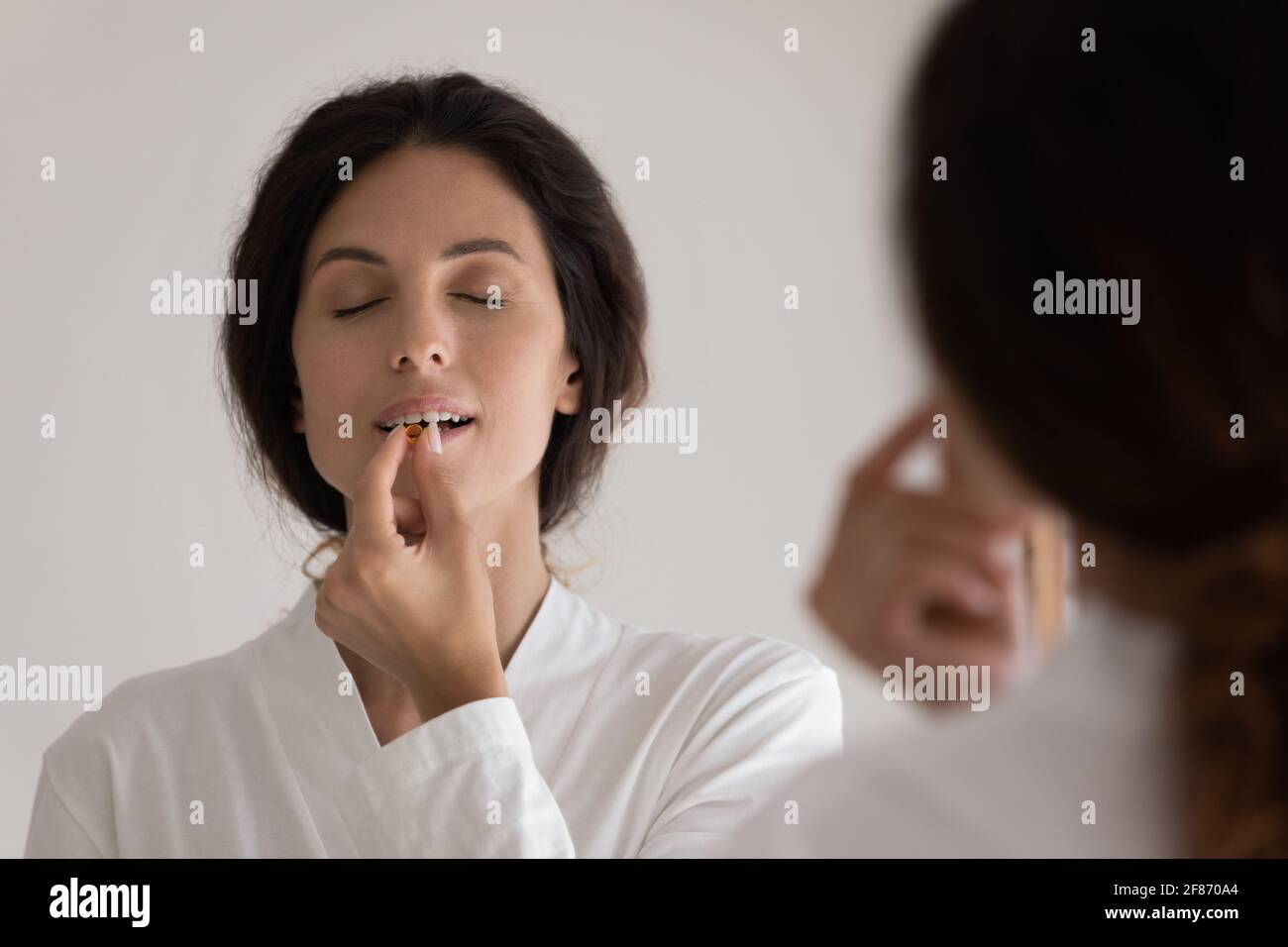 Close up mirror reflection smiling woman taking supplement, vitamin ...