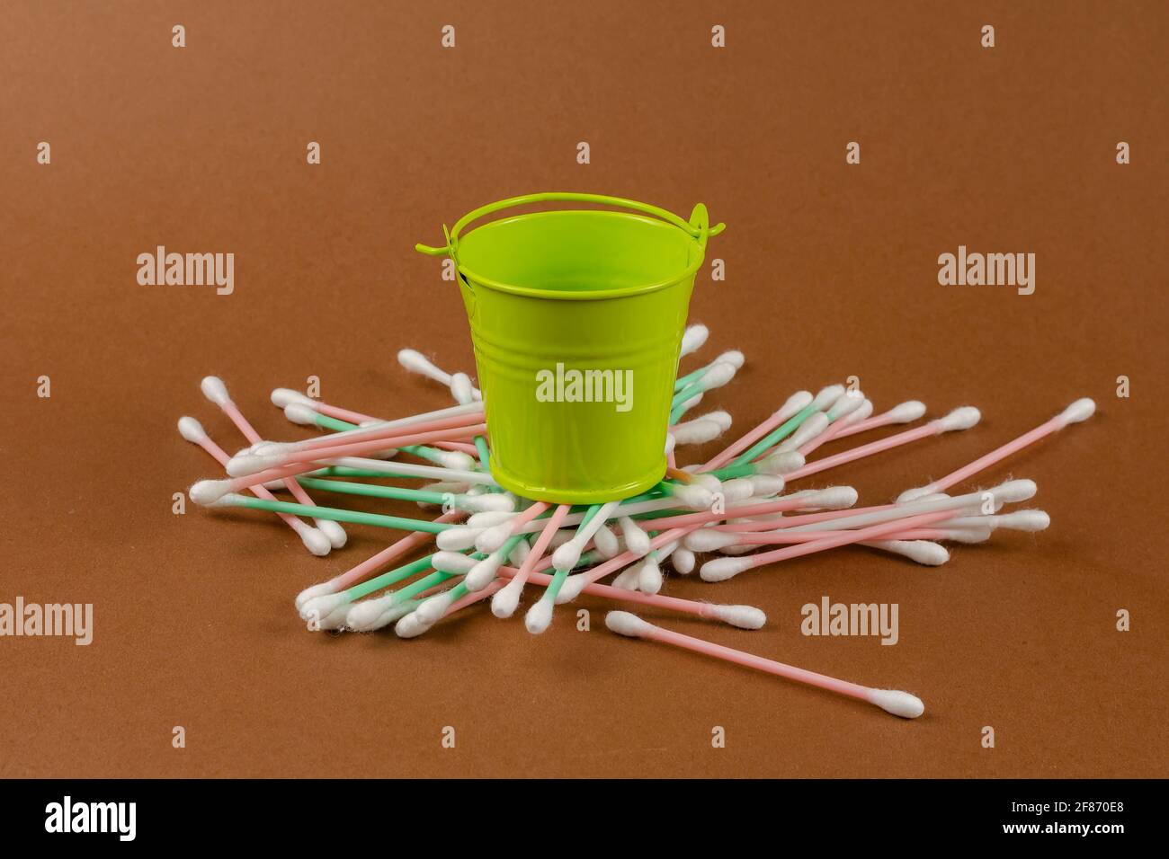 Small bucket and cotton swabs on a brown background. Empty green bucket ...