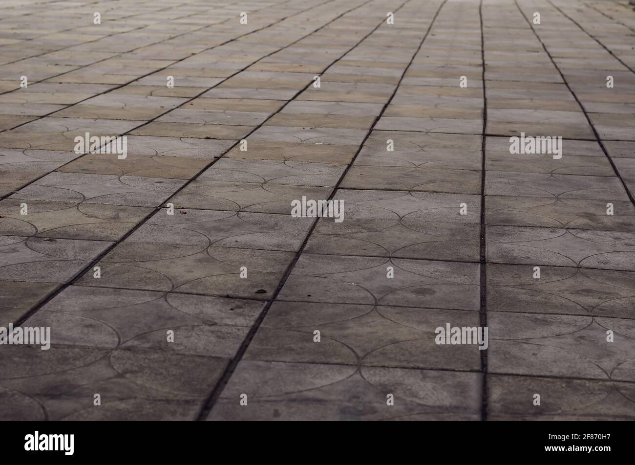 Gray sidewalk in tiles in a receding perspective. Repeating square ...