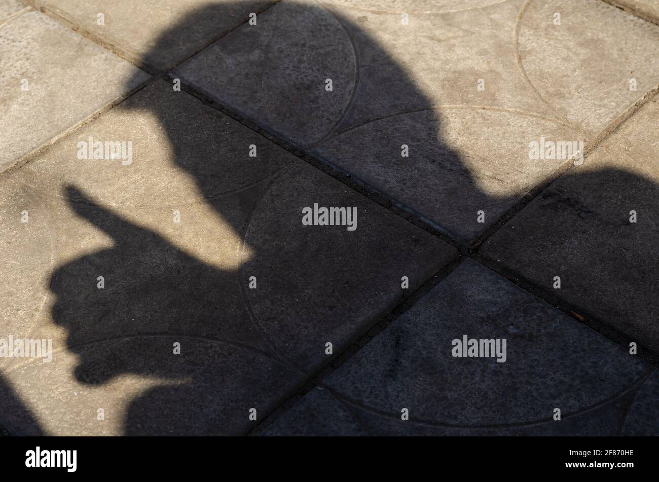 Male shadow on the sidewalk with a thumb up gesture. The silhouette of ...