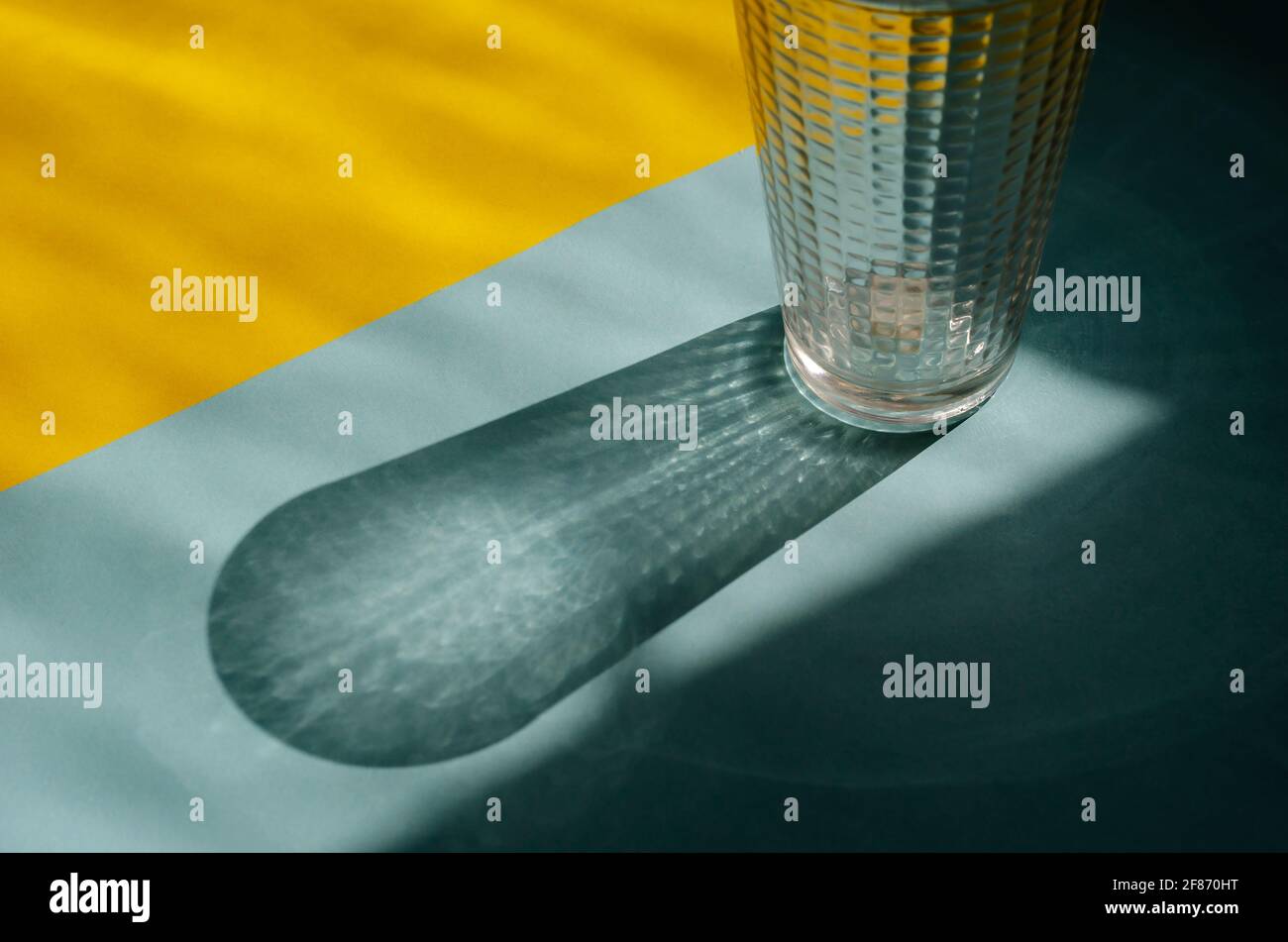 Minimalist light and shadow composition with an empty glass on a yellow ...
